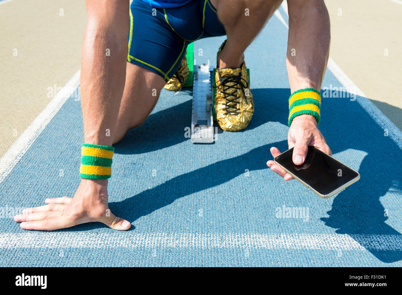 Athlete crouching at the starting line of a running track wearing ...