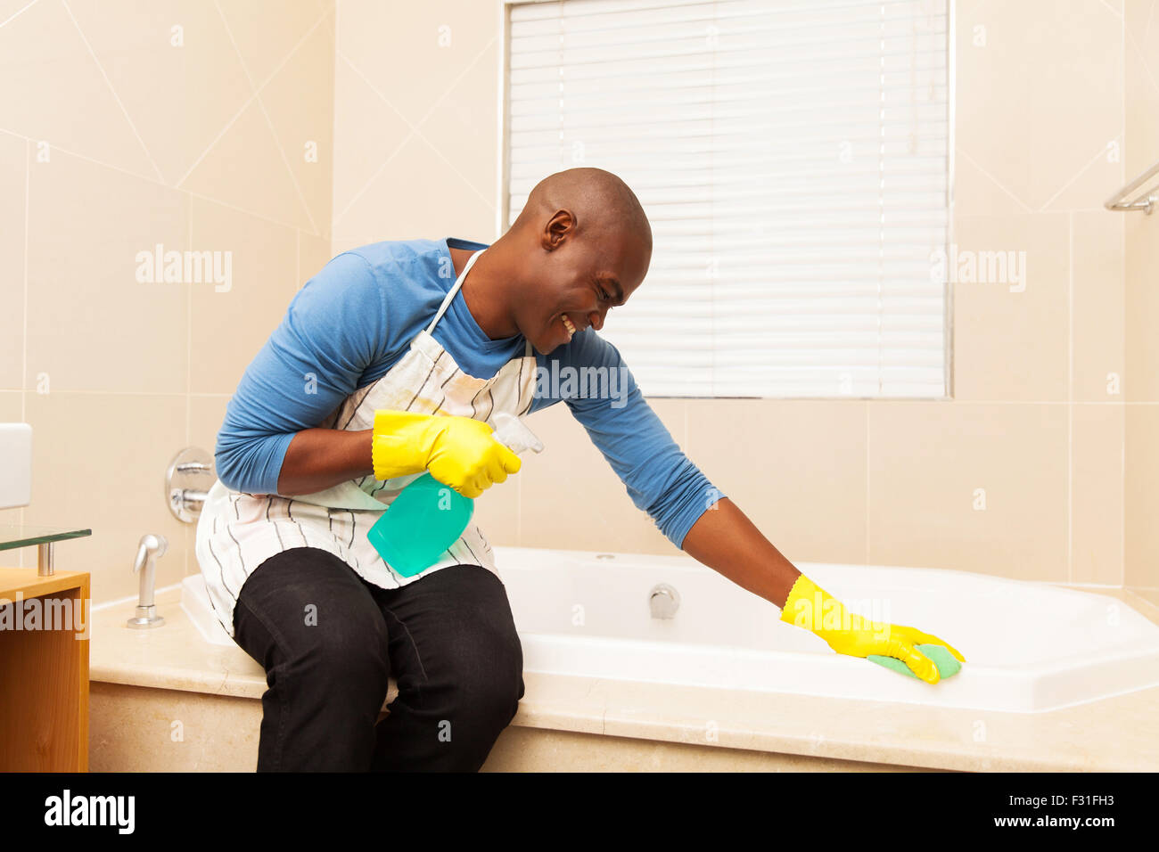 happy African American man cleaning up bathtub at home Stock Photo - Alamy