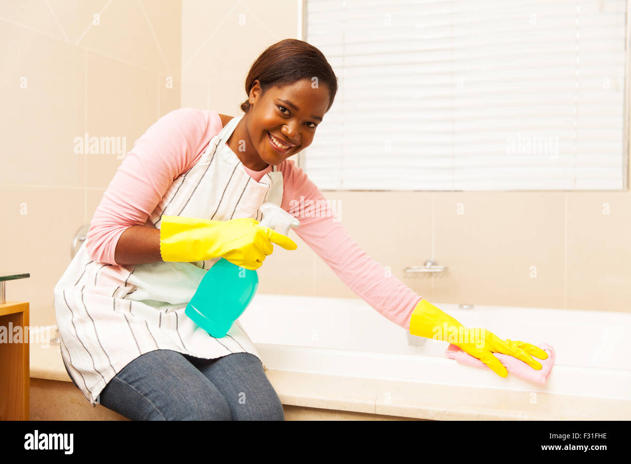 happy young African woman cleaning bathtub with a cloth Stock Photo - Alamy