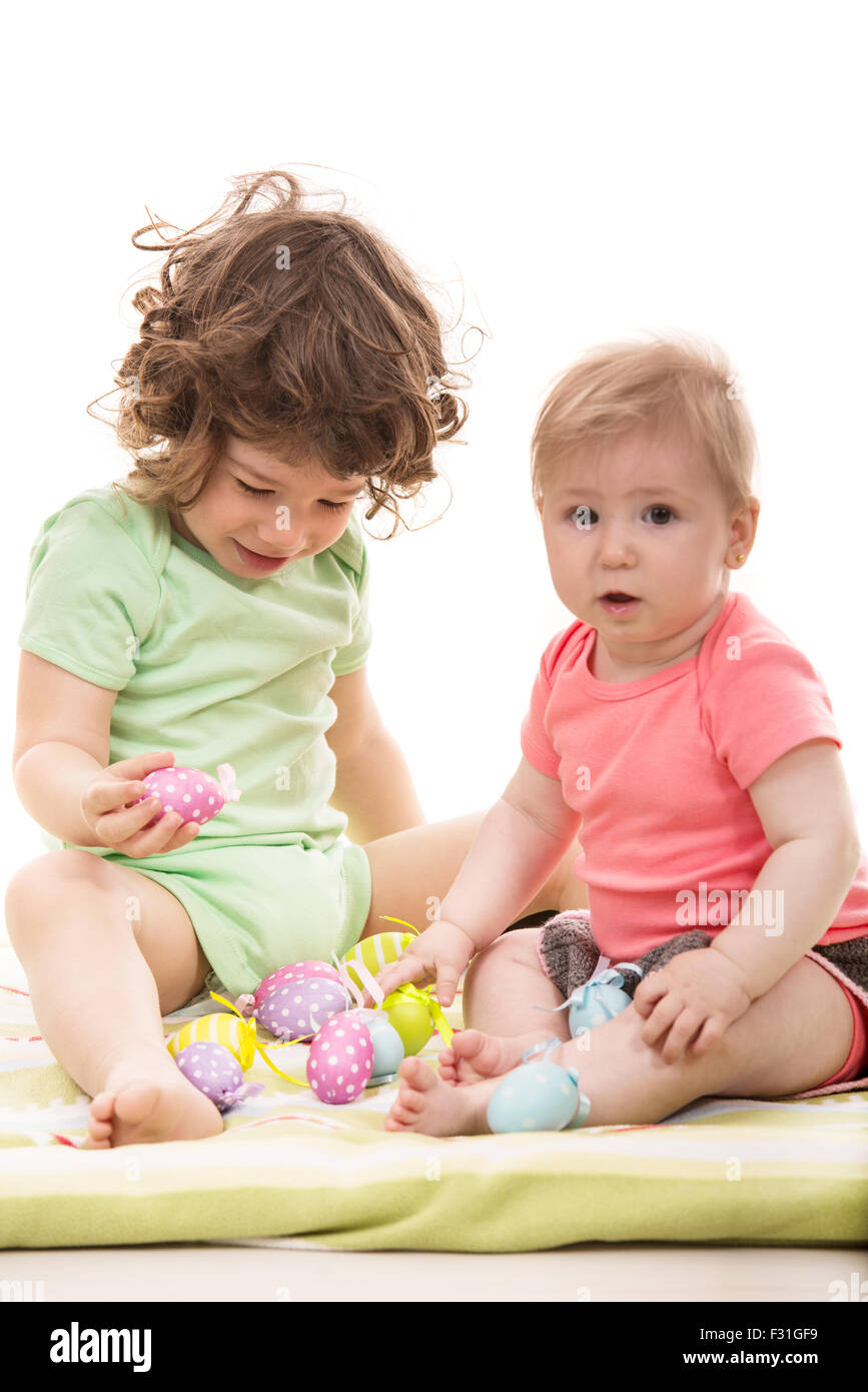 Two little kids playing with Easter eggs and sitting together on a ...