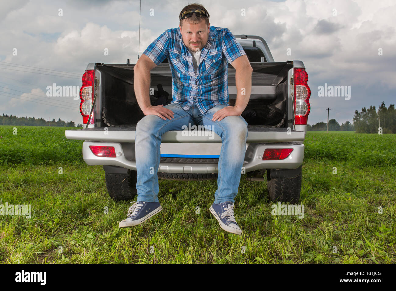 Solid man sitting on car trunk on natural background Stock Photo - Alamy