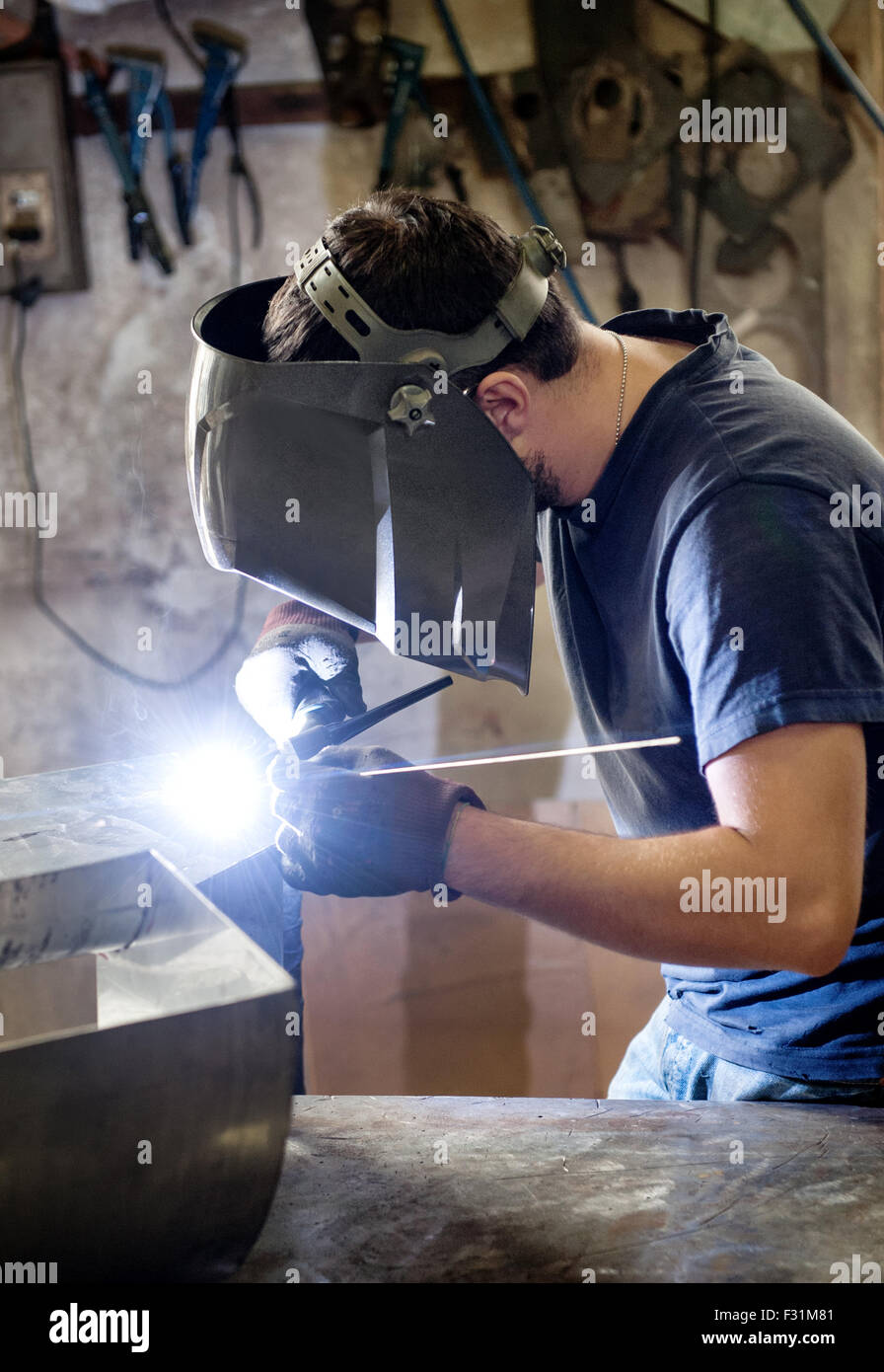 Welder or metalworker doing welding in an industrial metal workshop ...