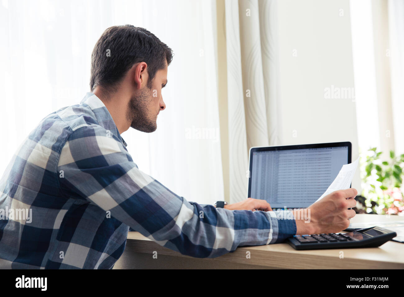 Portrait of a young man paying bills with his laptop at home Stock ...