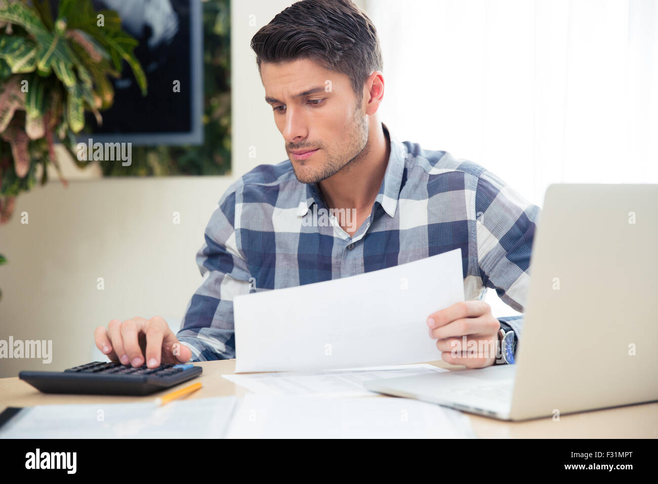 Portrait of a man with calculator checking bills at home Stock Photo ...
