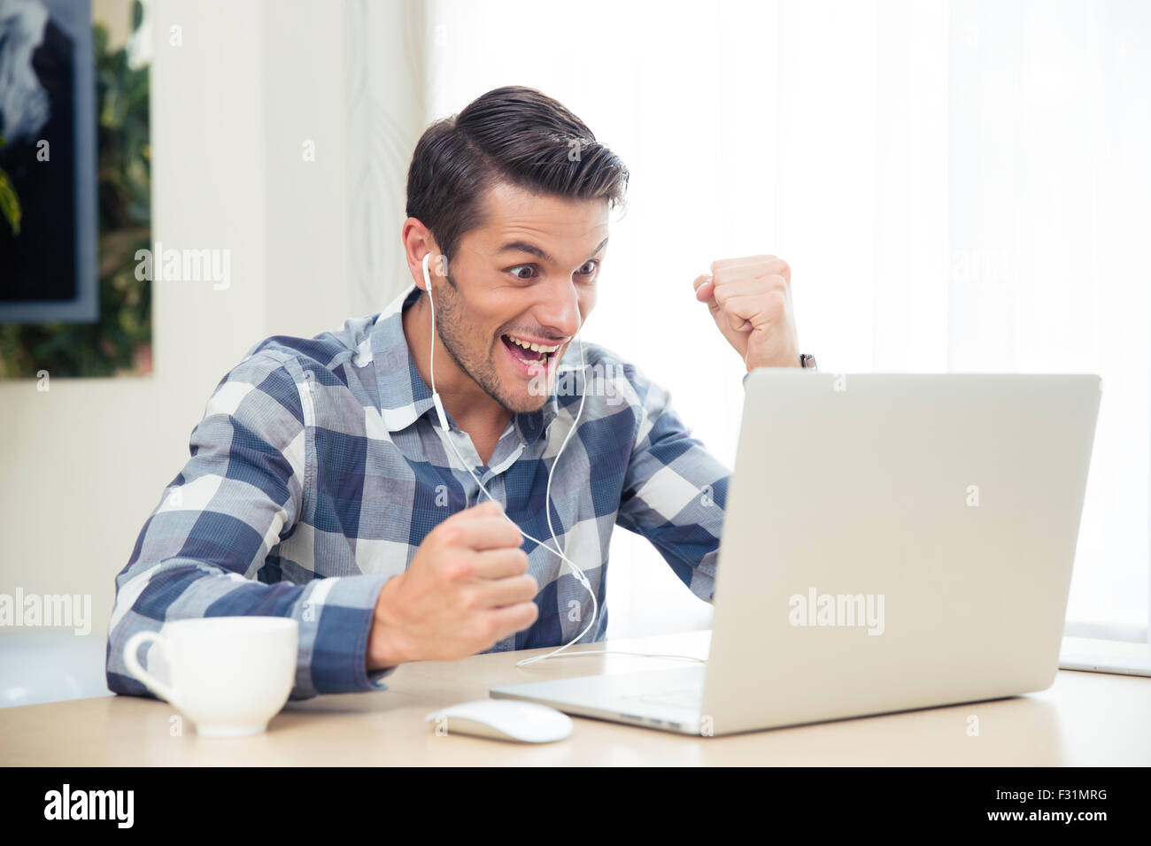 Portrait of a casual man watching the game on his laptop at home Stock ...