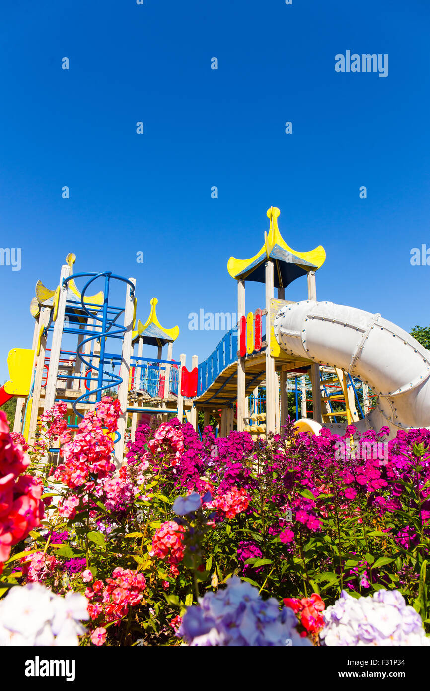 Kid's playground outdoors with flowers on foreground Stock Photo - Alamy