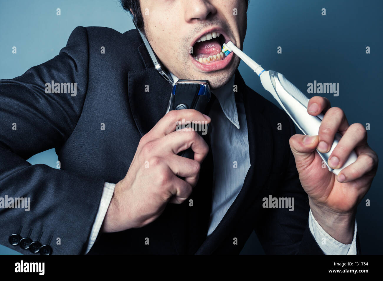 Stressed businessman is on the phone while brushing his teeth and ...