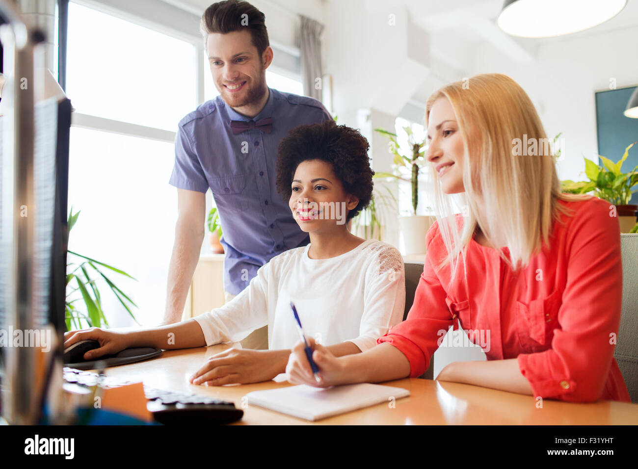 happy creative team with computer in office Stock Photo - Alamy