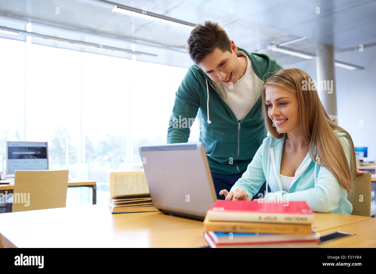 happy students with laptop in library Stock Photo - Alamy