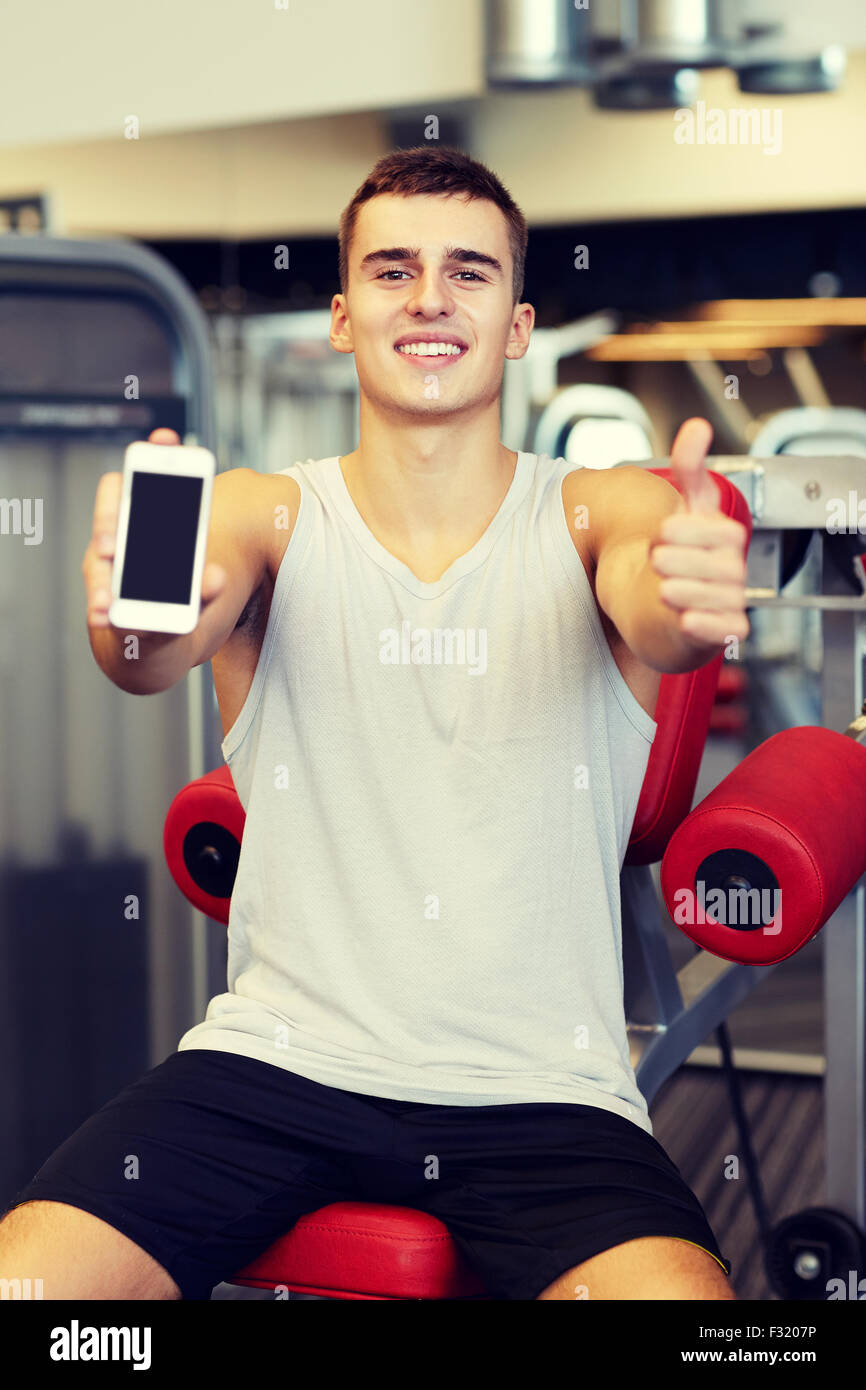 smiling young man with smartphone in gym Stock Photo - Alamy