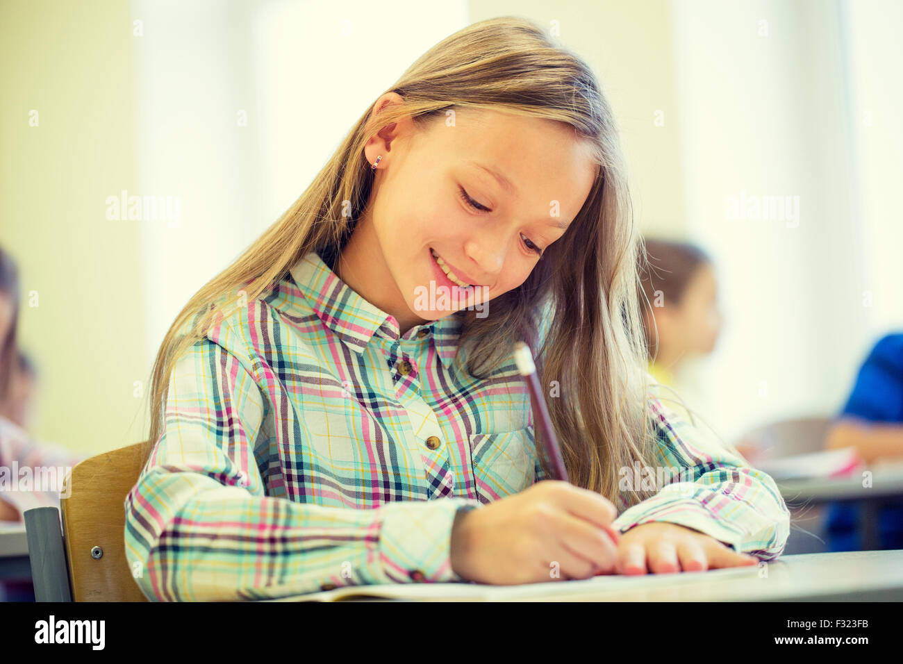 smiling school girl writing test in classroom Stock Photo - Alamy