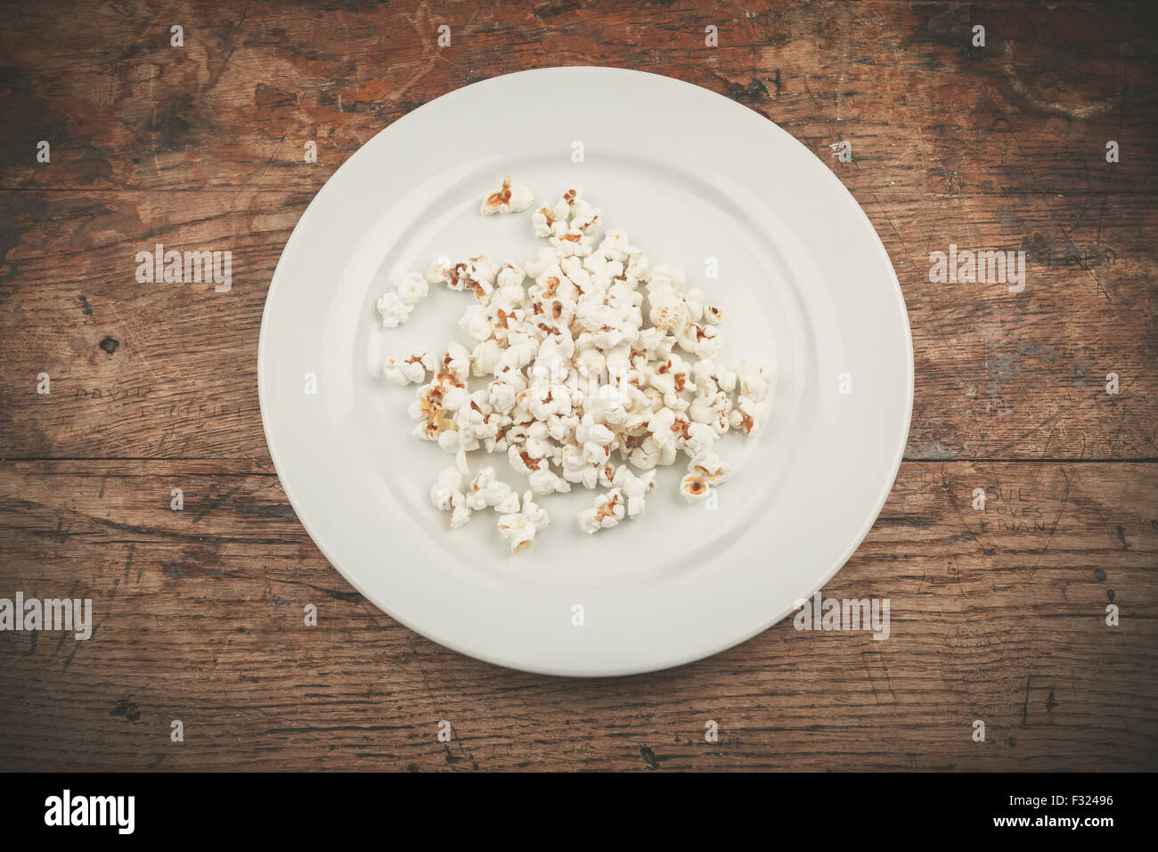 White plate with popcorn on wood table Stock Photo - Alamy