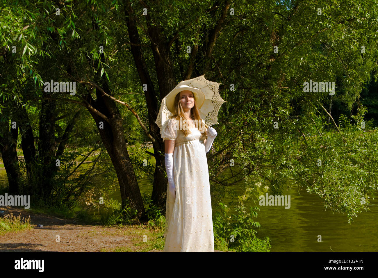Young beautiful lady in white historical dress with white hat and ...