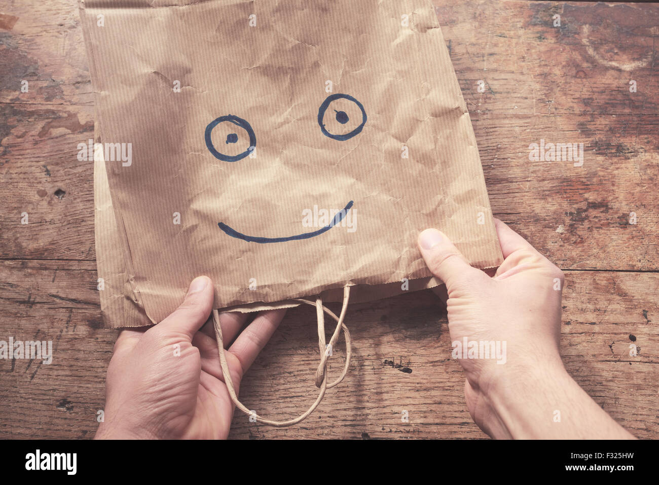 Man holding a paper bag with a smiling face painted on it Stock Photo ...