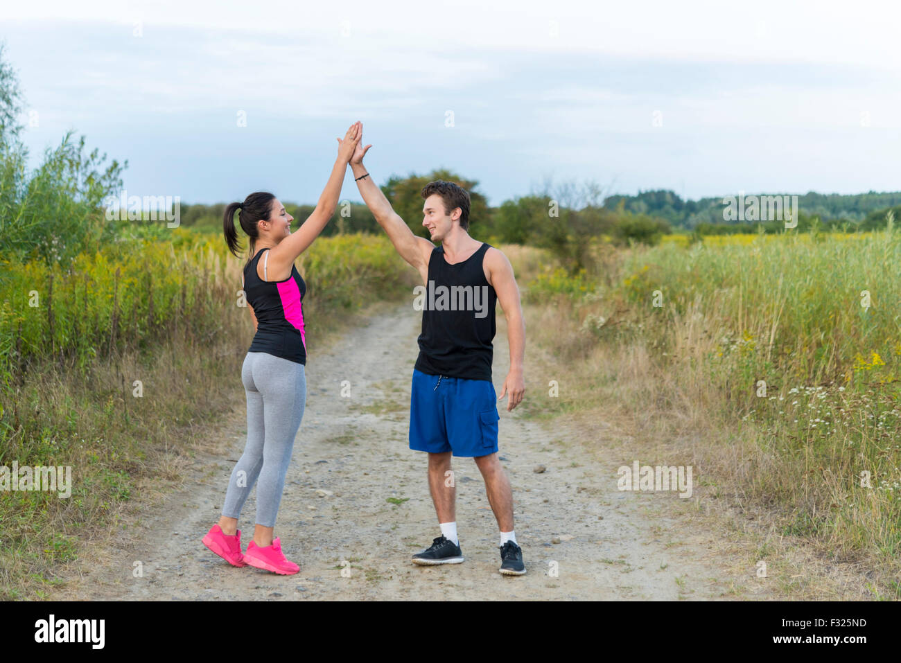 Two smiling young people making high five outdoors - training, healthy ...