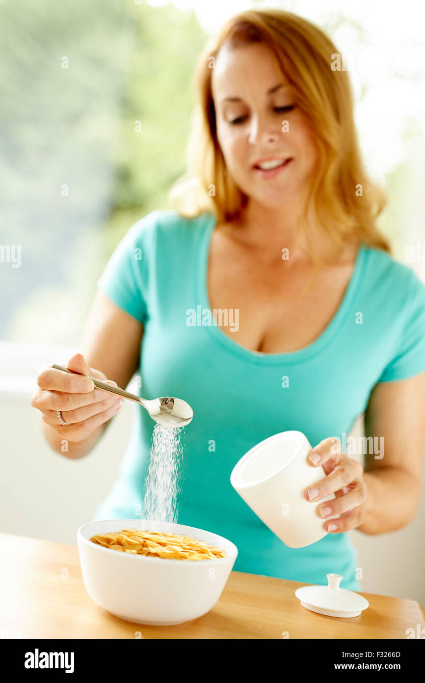 Girl pouring sugar on cereal Stock Photo - Alamy