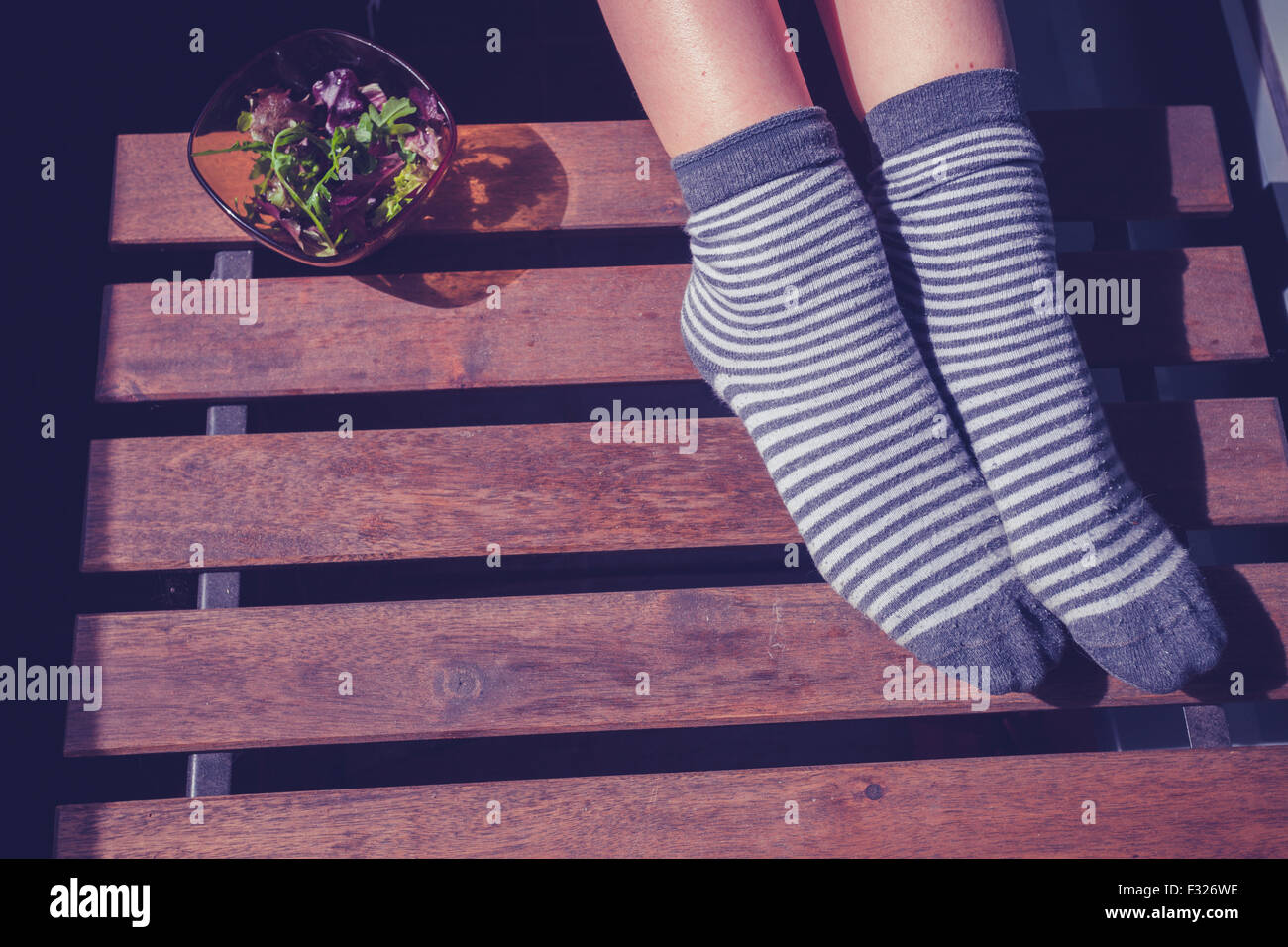 Young woman resting her legs on a table next to a bowl of salad Stock ...