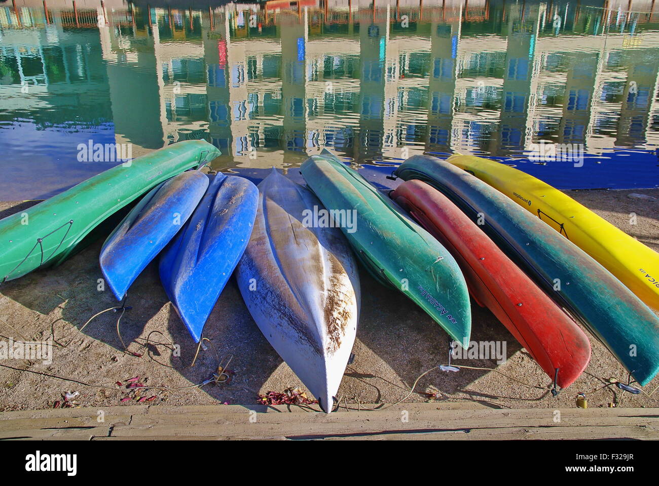 Colorful canoes lying on the banks of a resorts lake with refection of ...