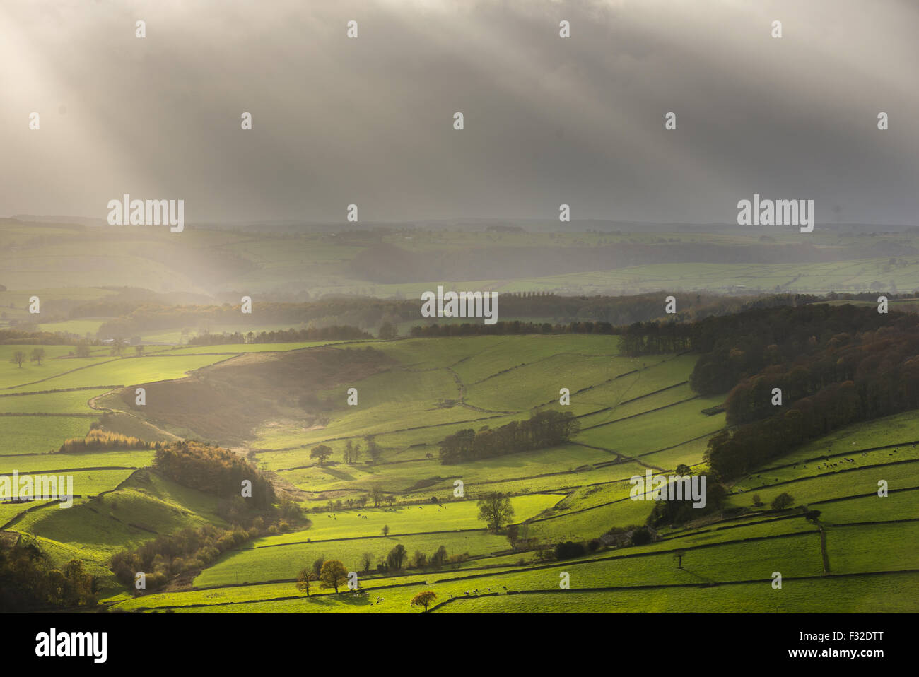 Sunbeams illuminating fields in rural landscape, near Baslow, seen from ...