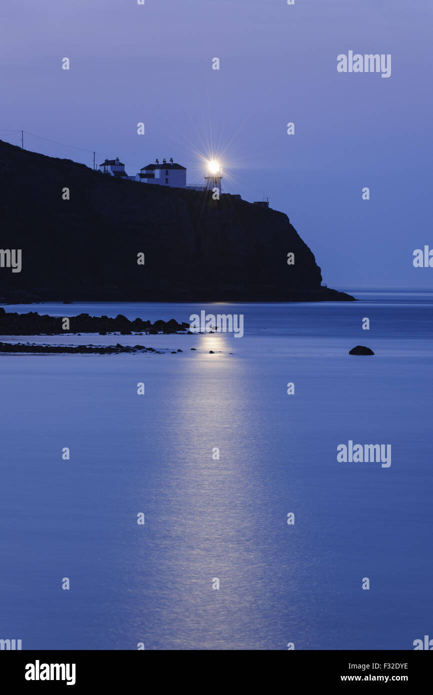 View of lighthouse on sea cliff at dusk, Blackhead Lighthouse ...