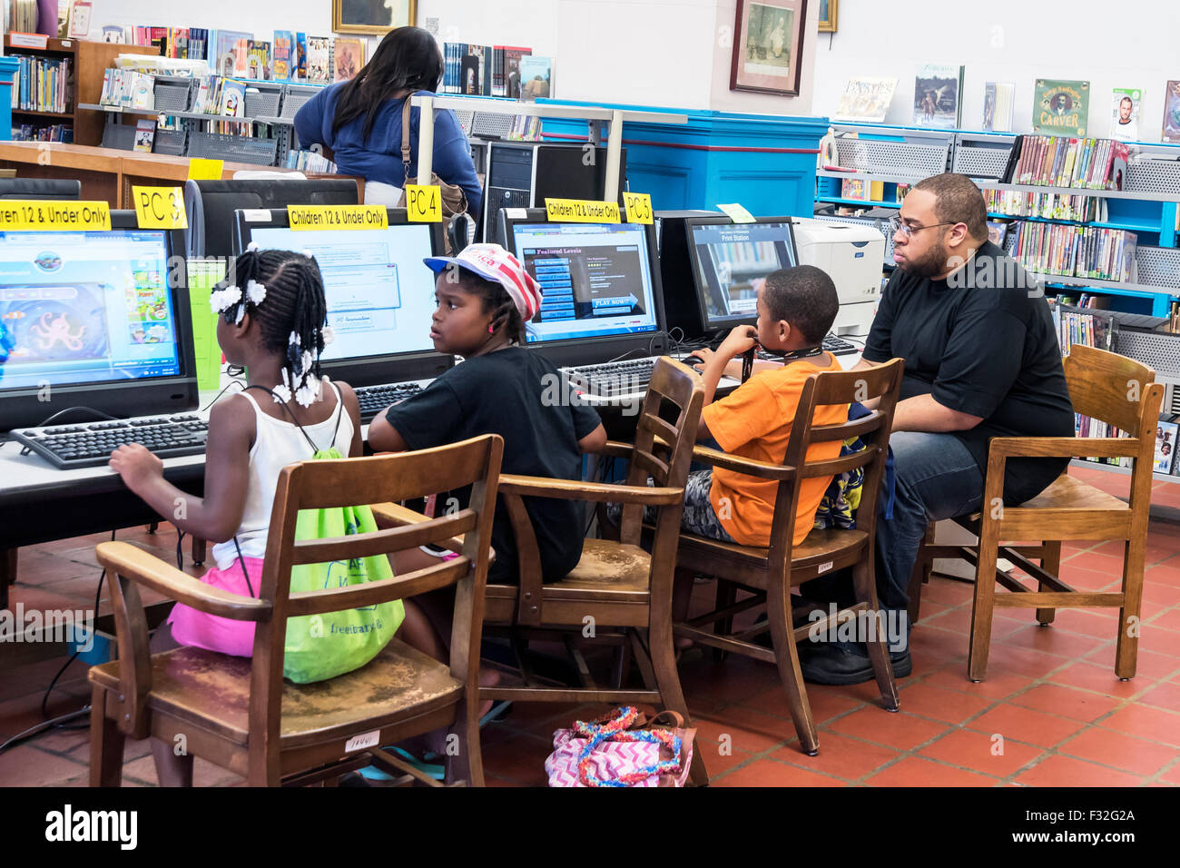 Adult African American and 3 kids working with computers in ...