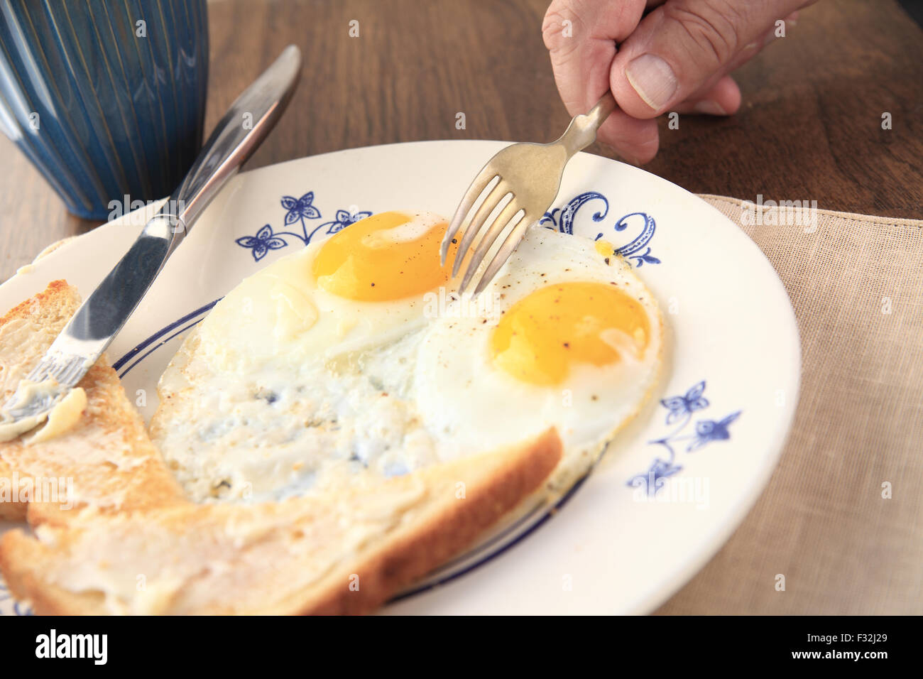 A man with a plate of fried eggs and buttered toast Stock Photo - Alamy