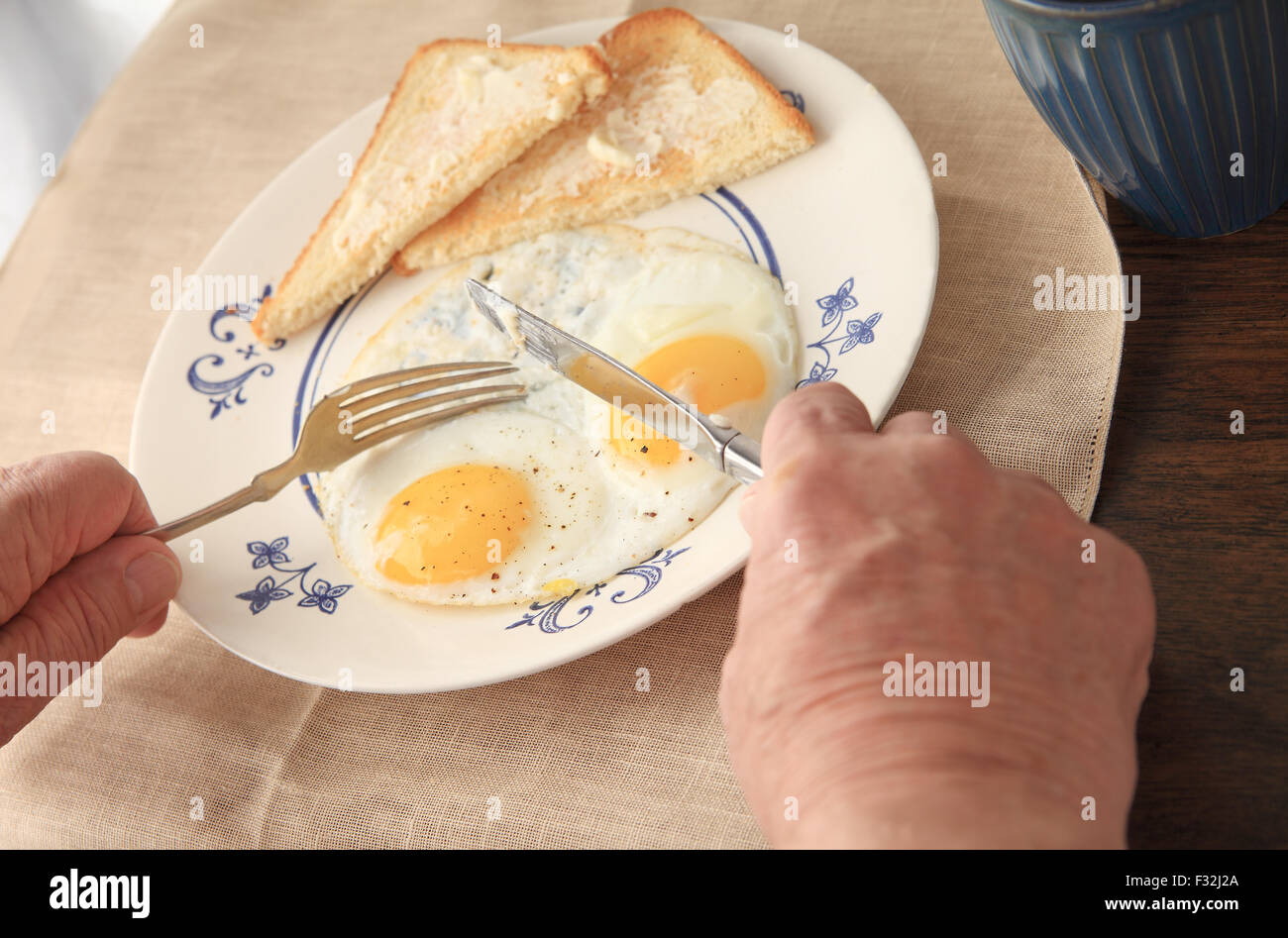 A man eating a breakfast of fried eggs and buttered toast Stock Photo ...