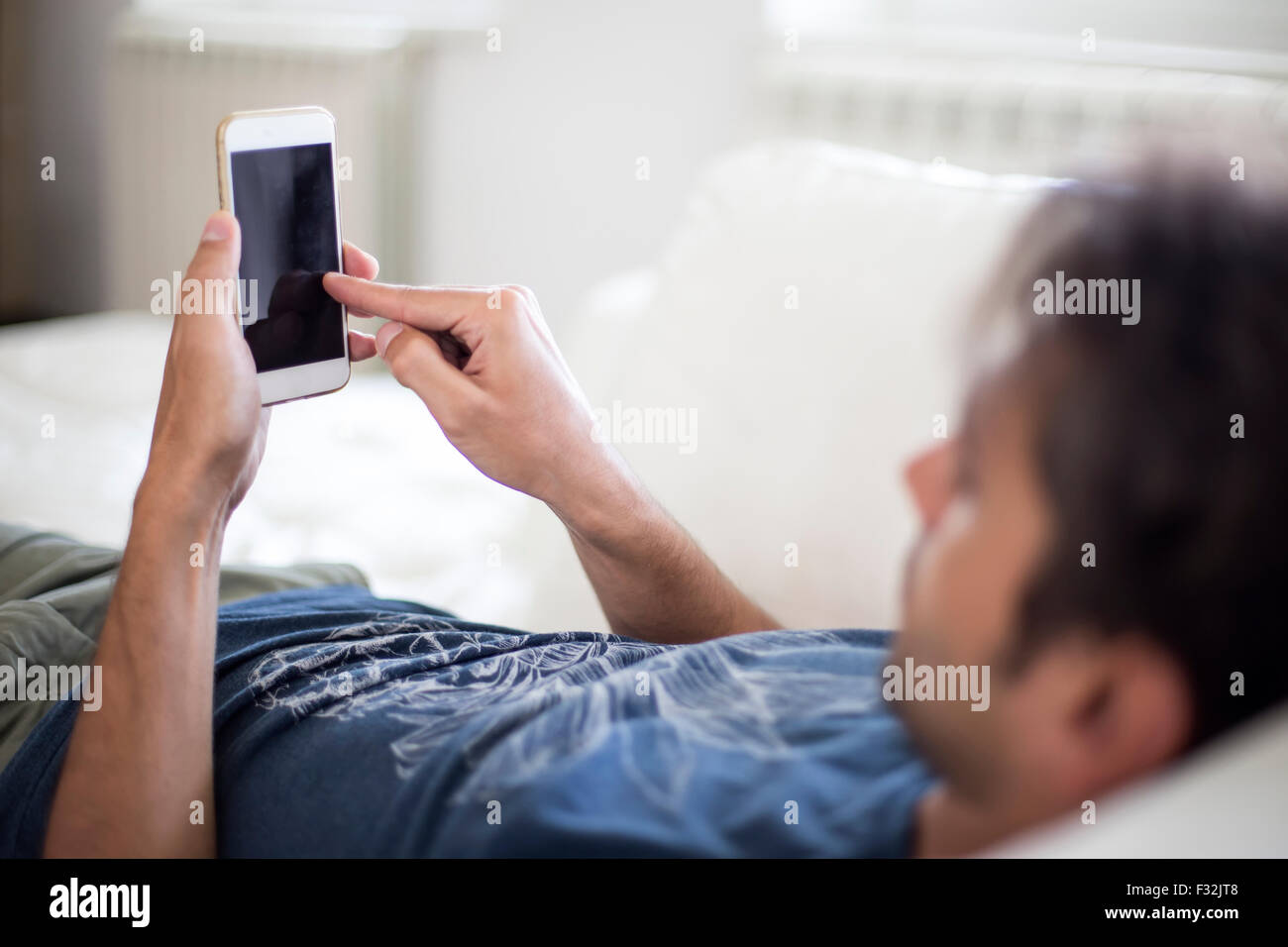 Man messaging with mobile on sofa hi-res stock photography and images ...