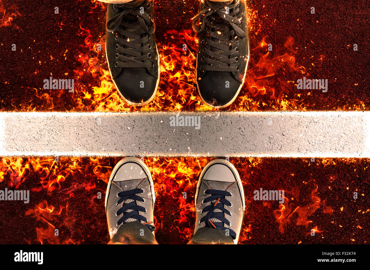 Feet in sneakers, standing next to white street lines in flame. Fire ...