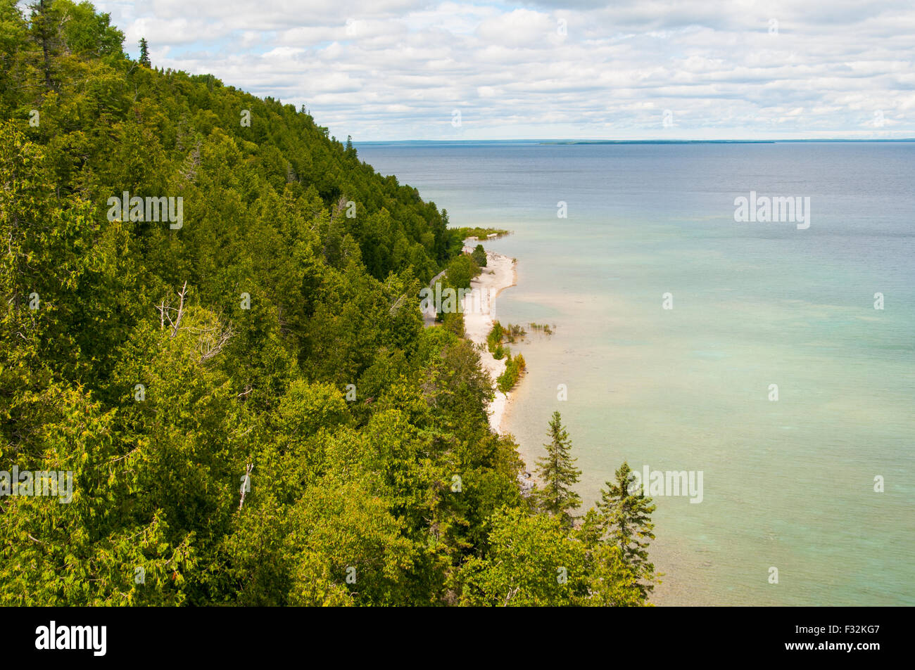 looking down a tree covered hillside into a clean clear lake Stock ...