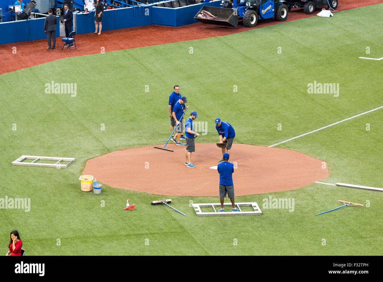 Grounds crew prepares the home plate area for a baseball game at Rogers ...