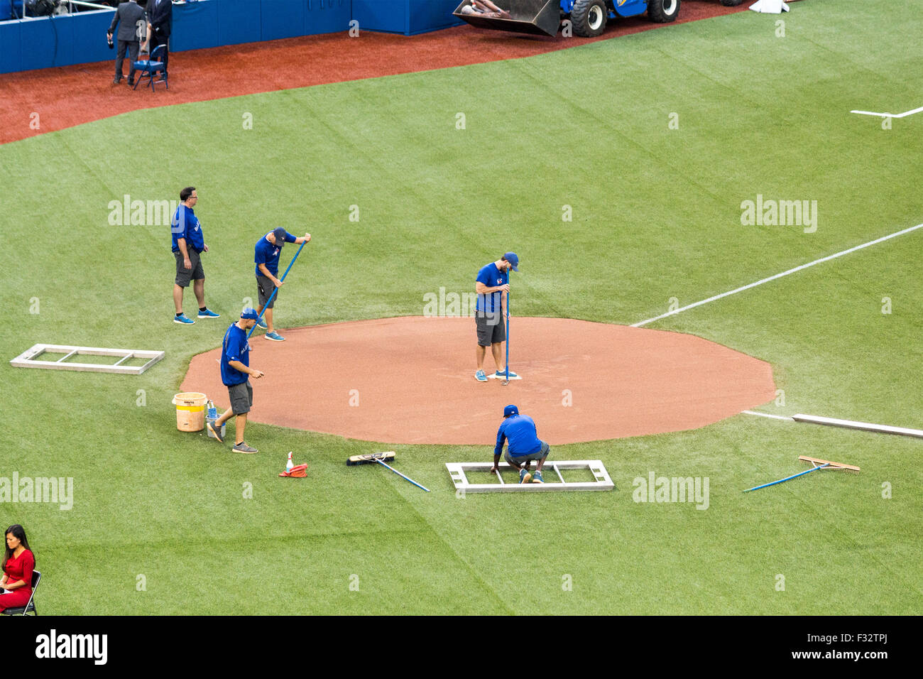 Grounds crew prepares the home plate area for a baseball game at Rogers ...