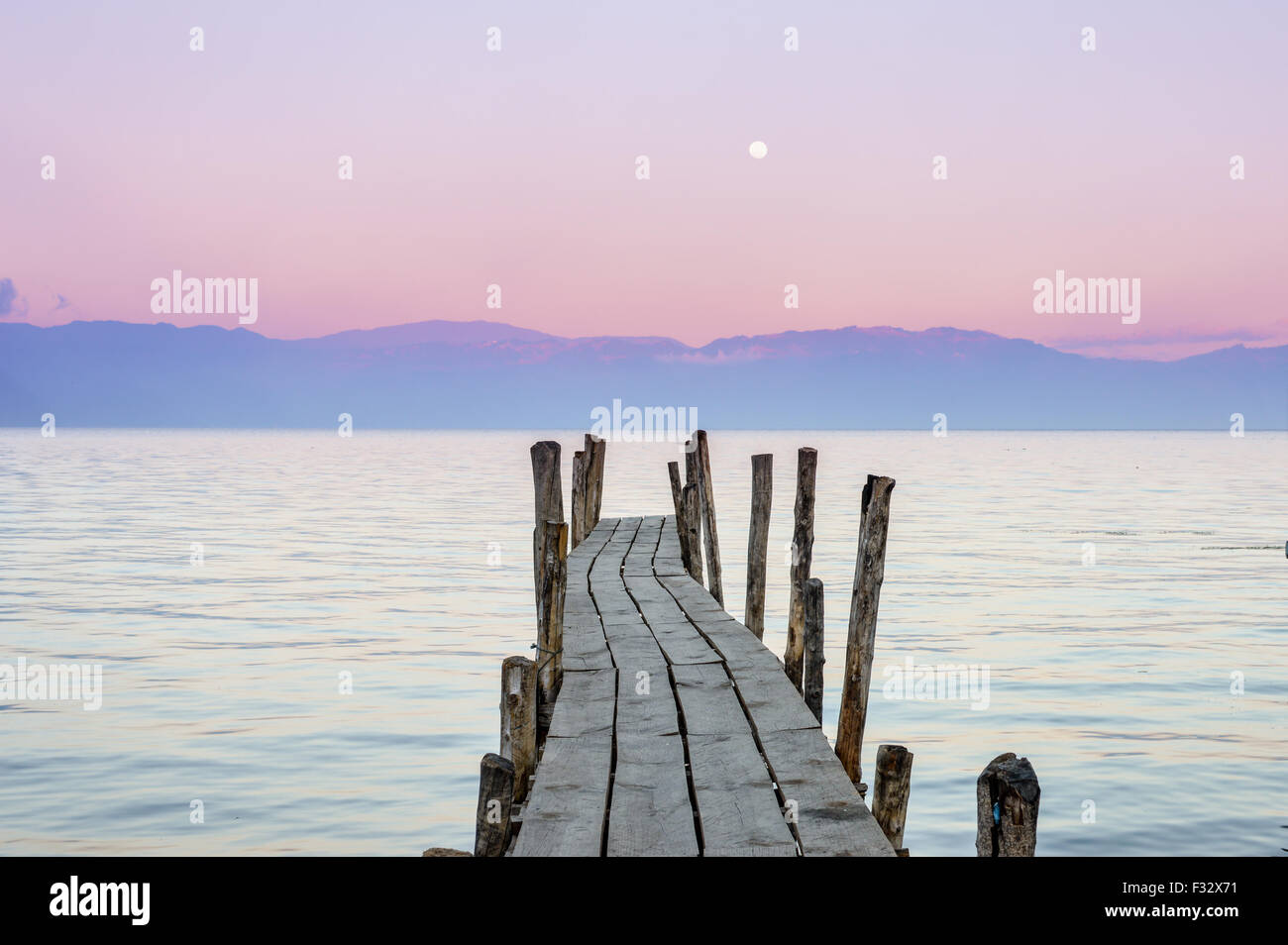 Little wooden boat dock with the pink sunset sky on the background in ...