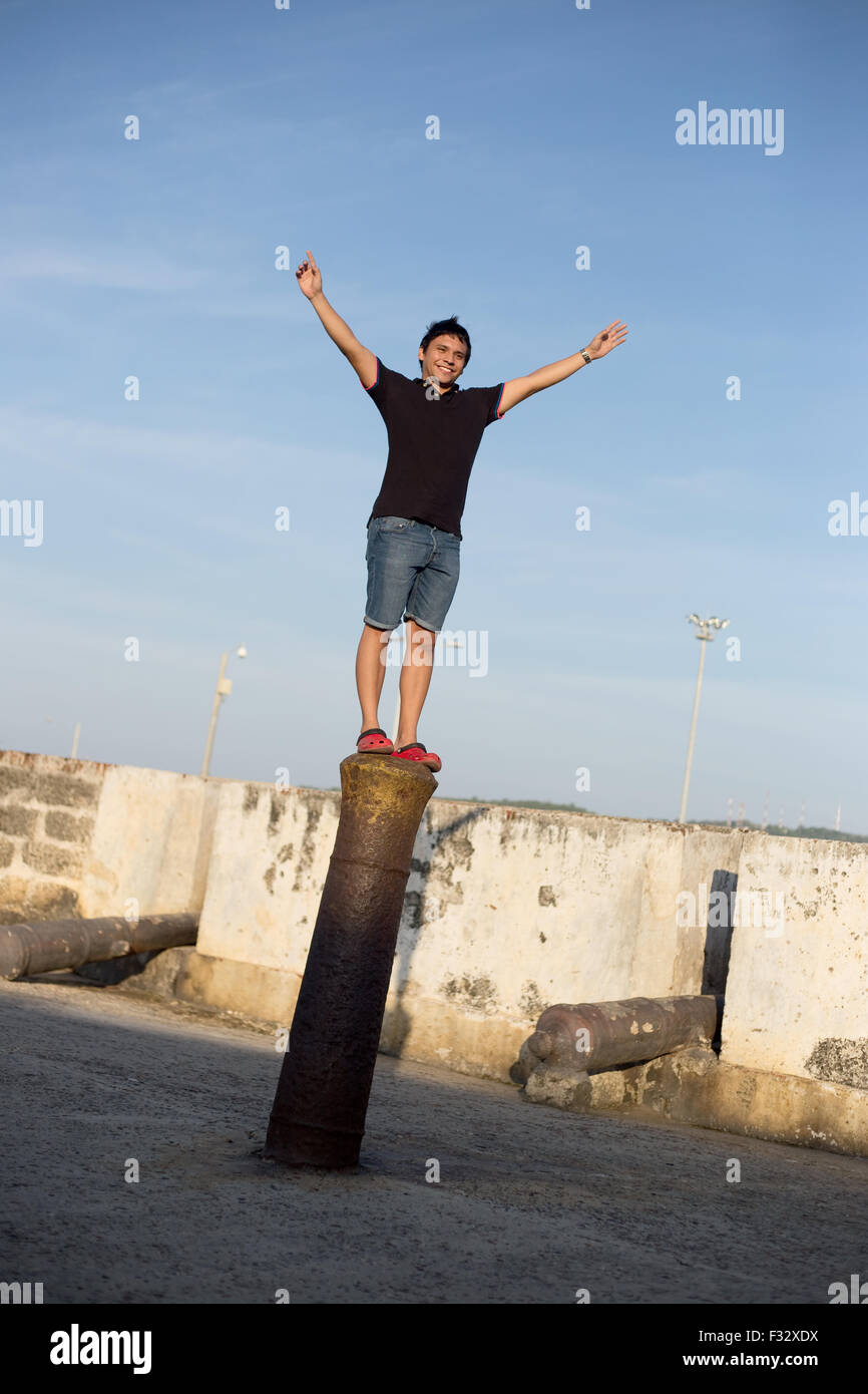 young man having fun standing on a metal pole Stock Photo - Alamy