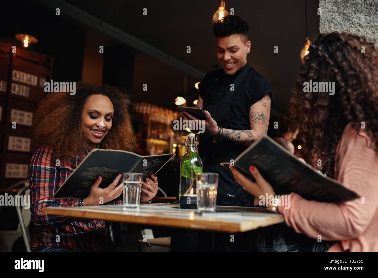 Young women seated at a table holding menus in a restaurant. Young ...