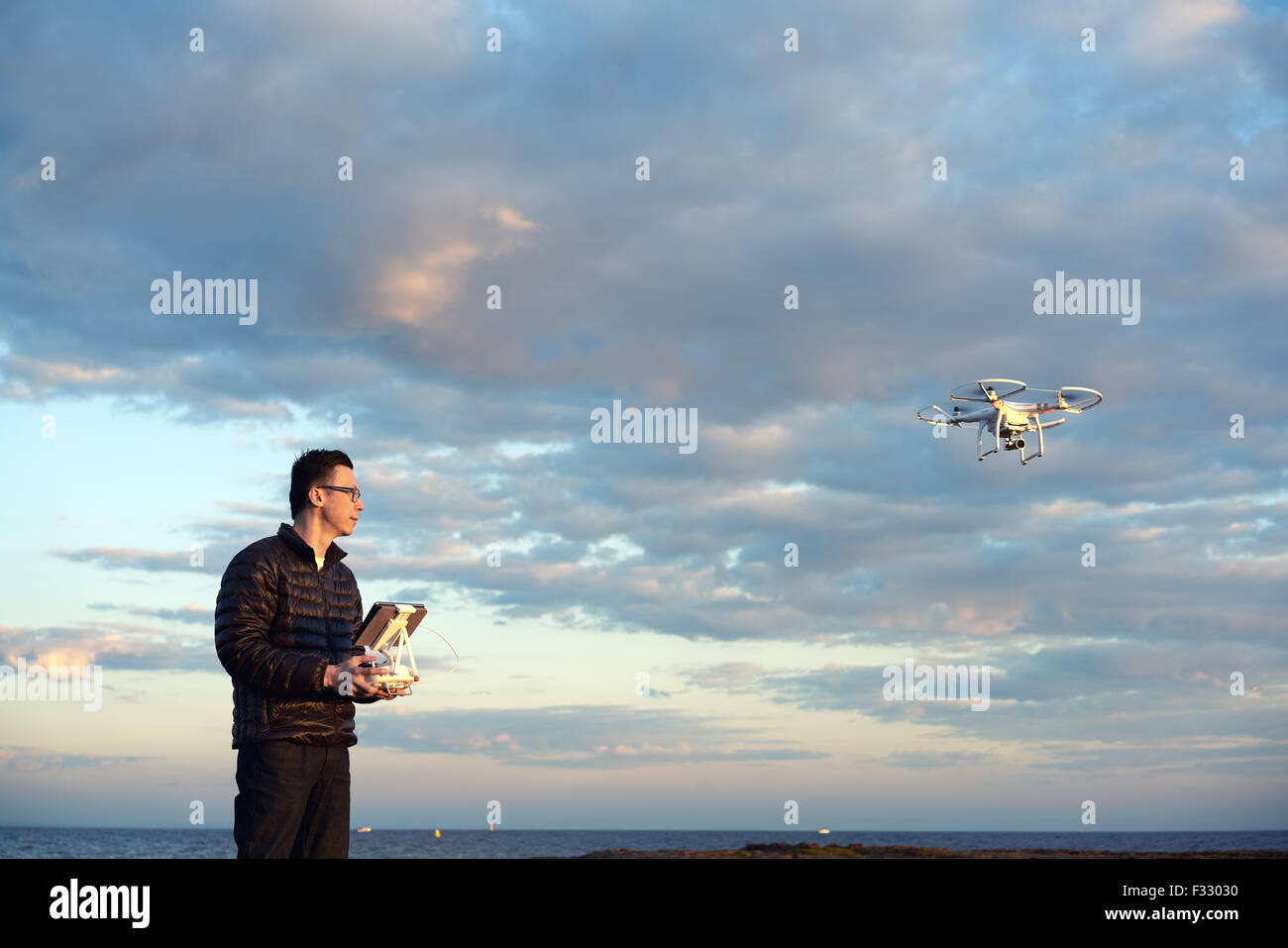 man flying quadcopter with remote control at the beach at sunset Stock ...