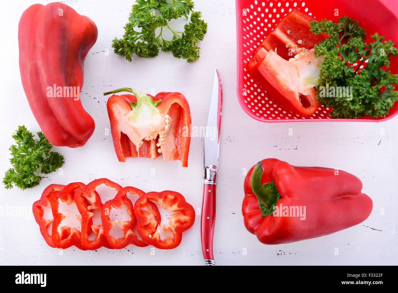 Red capsicum peppers, whole and sliced, with knife, parsley and ...