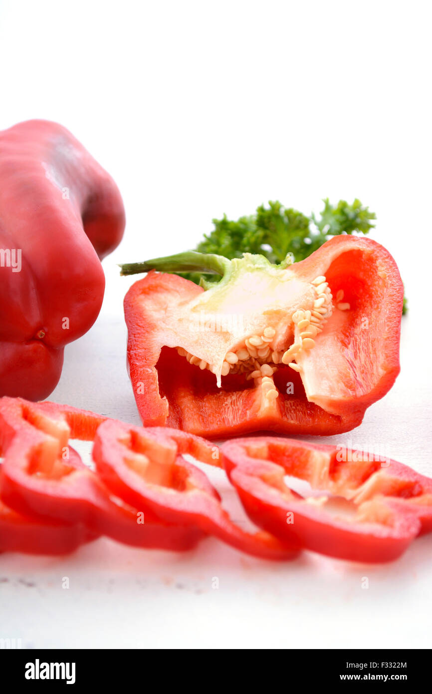 Red capsicum peppers, whole and sliced, with knife and parsley on white ...