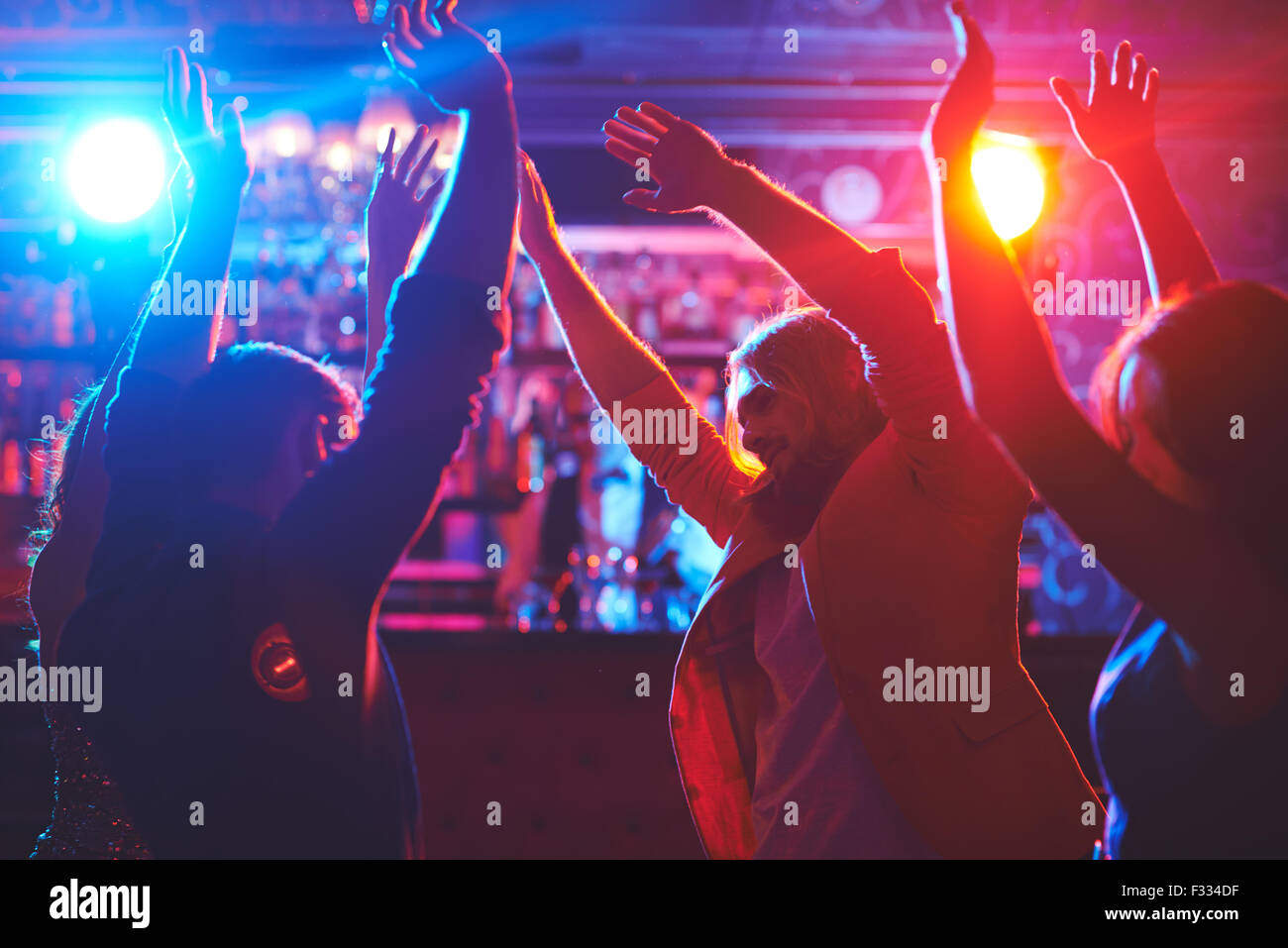 Happy friends with raised arms dancing at night club Stock Photo - Alamy