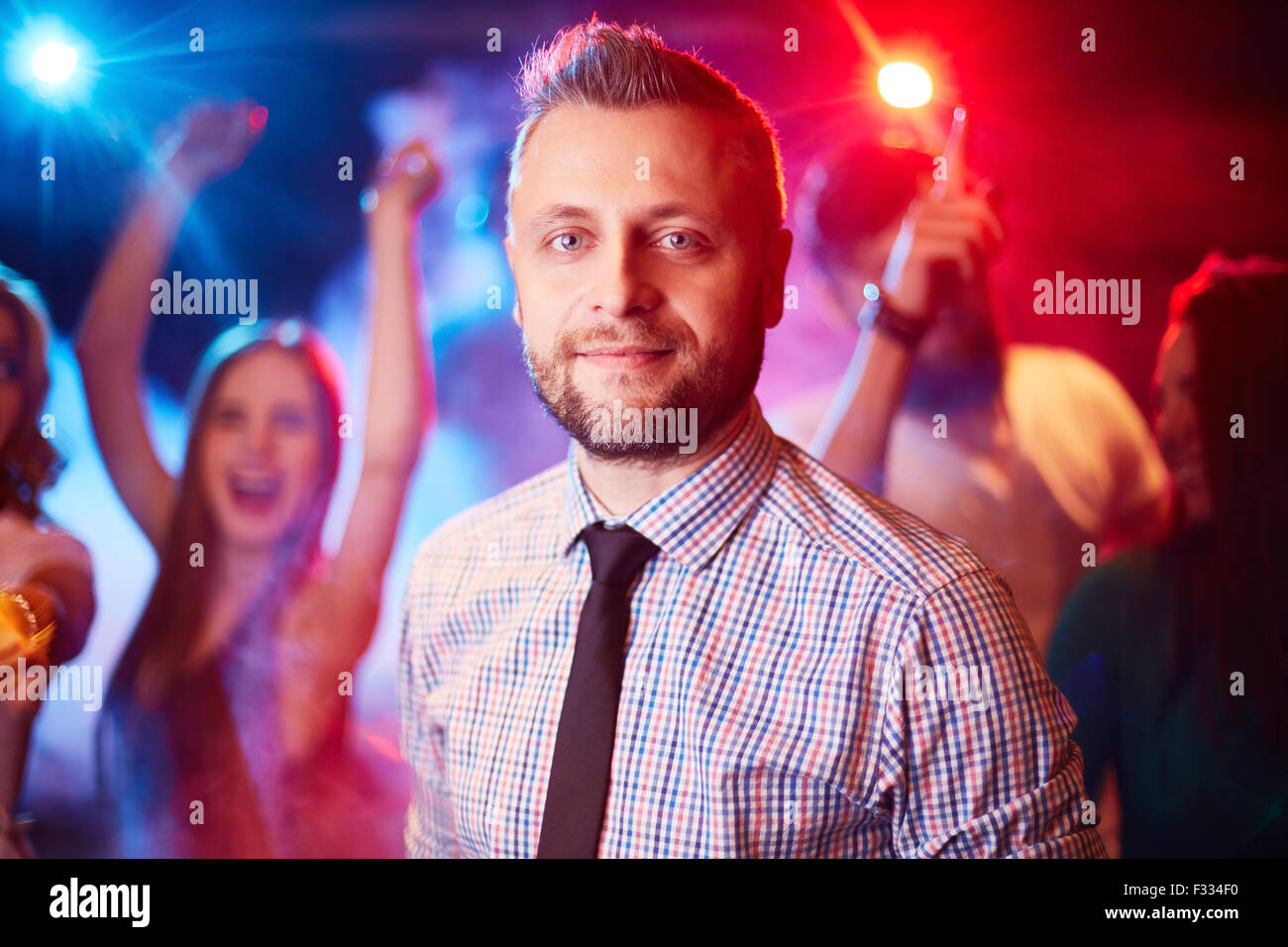 Handsome man looking at camera at party on background of dancing ...