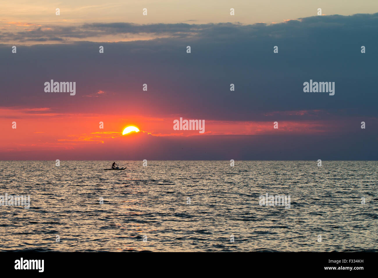 Man rowing on a traditional italian boat "pattino" while the sun is ...