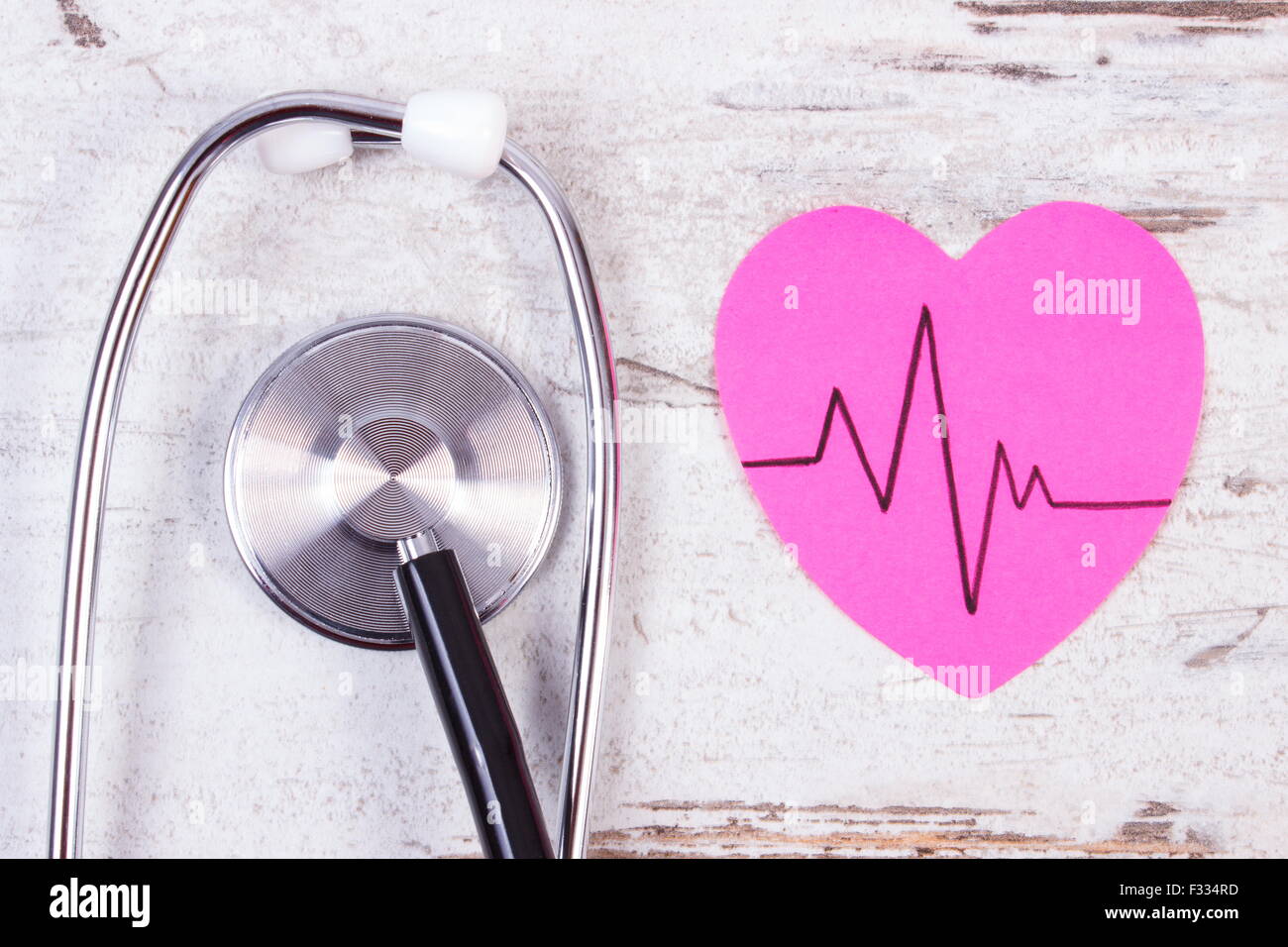 Pink heart of paper with electrocardiogram line and medical stethoscope ...