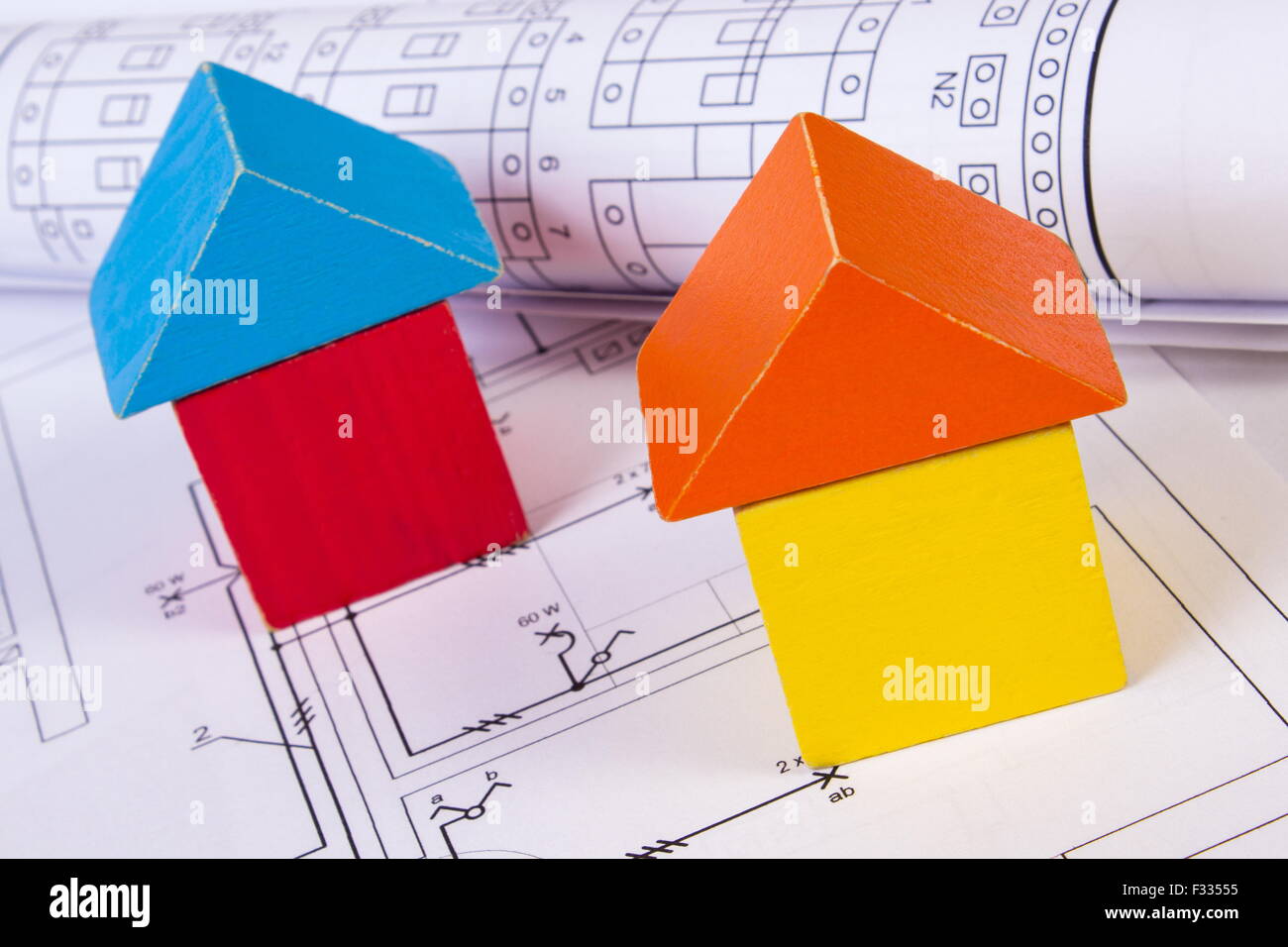 Houses shape made of wooden blocks and rolls of diagrams lying on ...