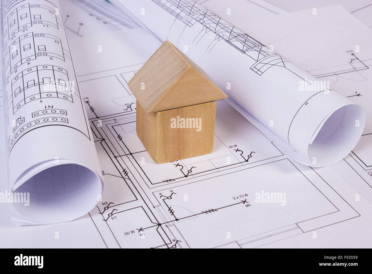 House shape made of wooden blocks and rolls of diagrams lying on ...