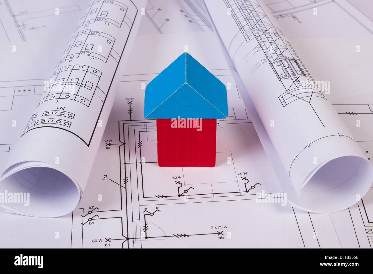 House shape made of wooden blocks and rolls of diagrams lying on ...