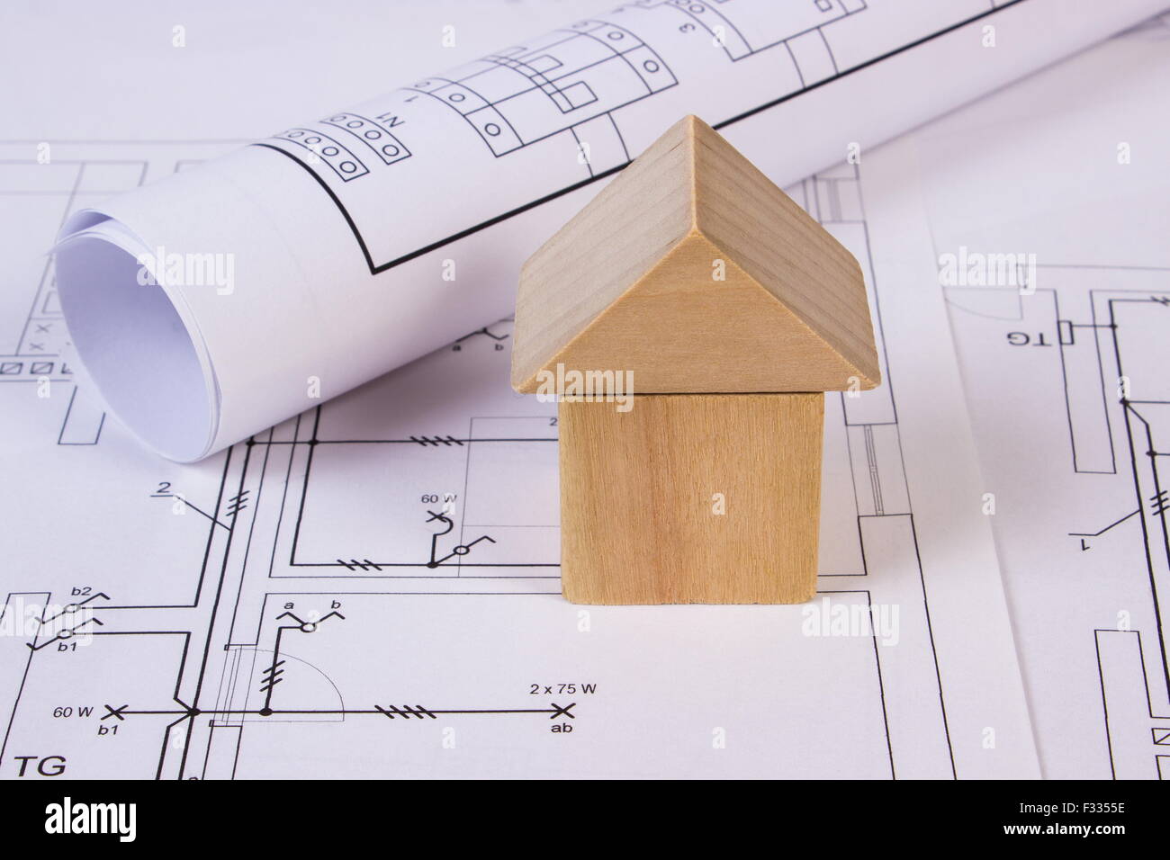 House shape made of wooden blocks and rolls of diagrams lying on ...