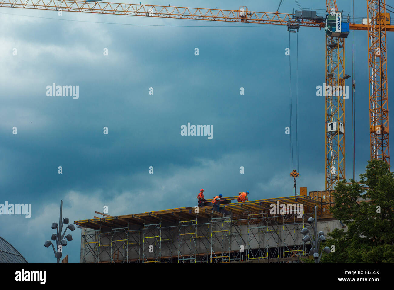 A photography of a building being built by construction workers against ...