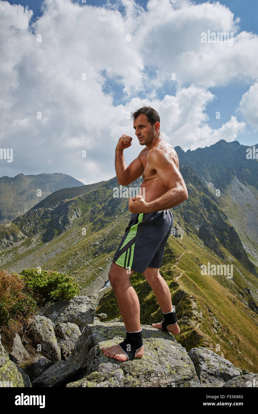 Kickboxer or muay thai fighter practicing shadow boxing on a mountain ...