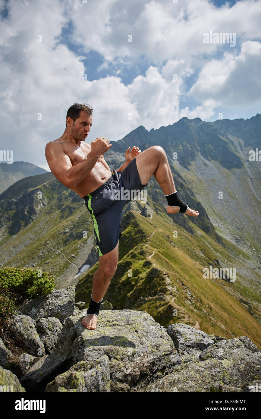 Kickboxer or muay thai fighter practicing shadow boxing on a mountain ...