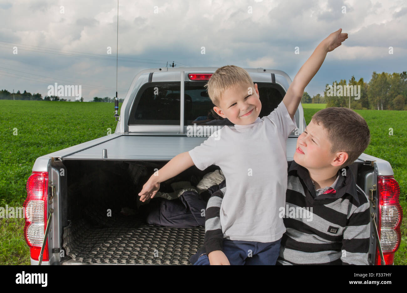 Two brothers siiting on a car trunk on natural background Stock Photo ...
